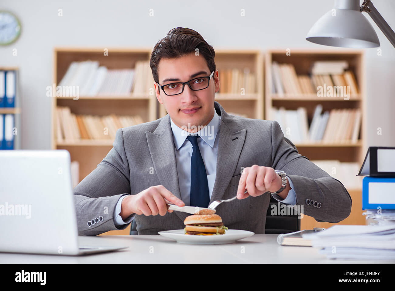 Hungry funny businessman eating junk food sandwich Stock Photo - Alamy
