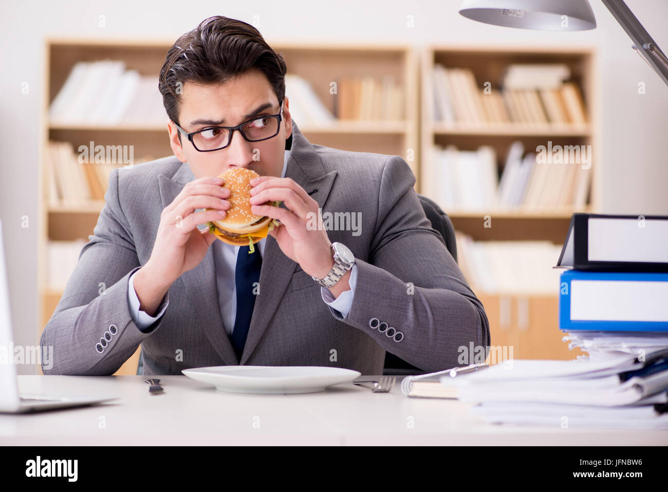 Hungry funny businessman eating junk food sandwich Stock Photo - Alamy