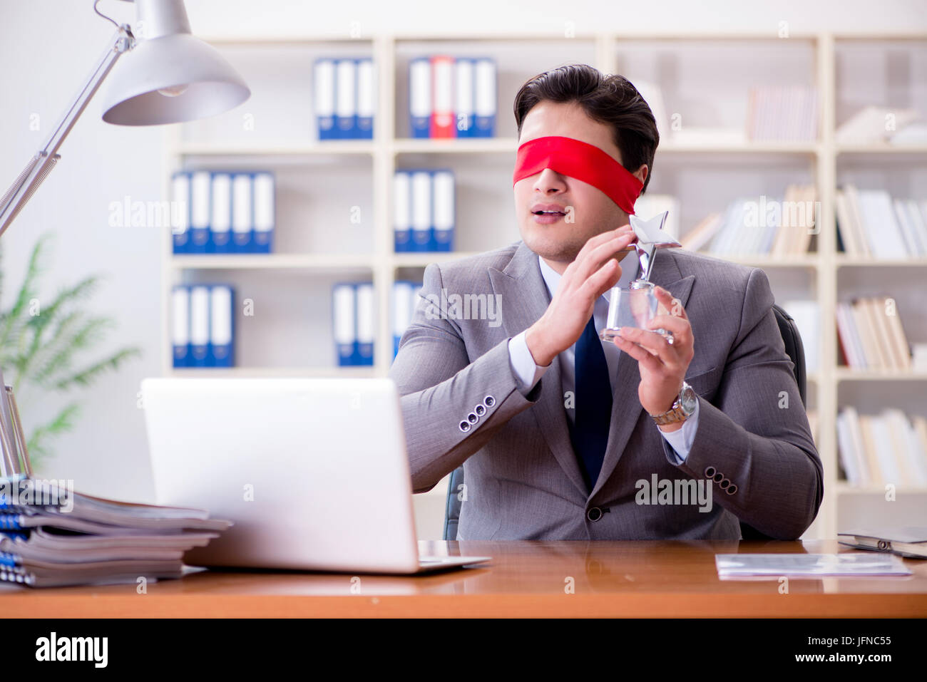 Blindfold businessman sitting at desk in office Stock Photo - Alamy