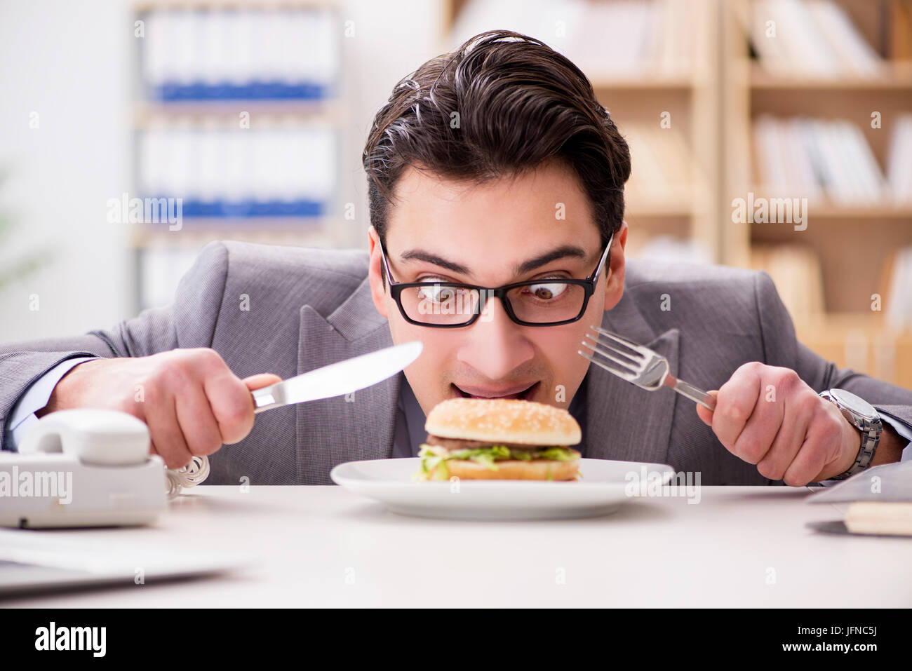 Hungry funny businessman eating junk food sandwich Stock Photo - Alamy