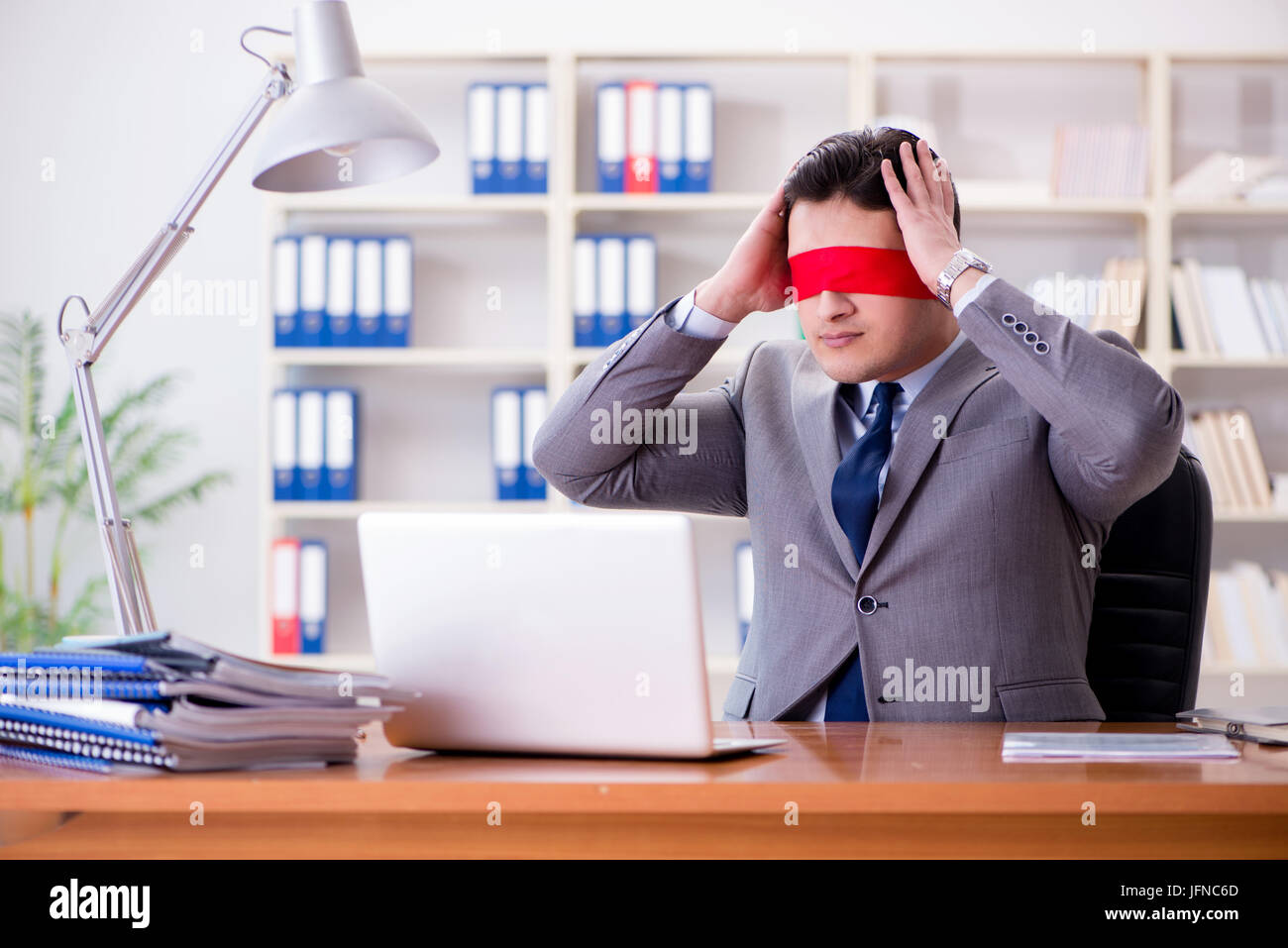 Blindfold businessman sitting at desk in office Stock Photo - Alamy