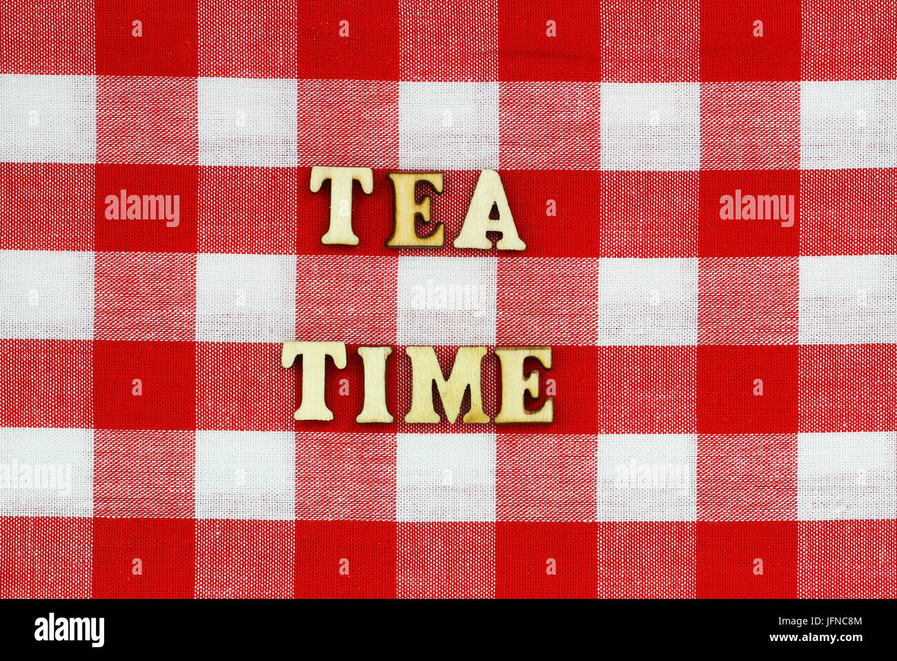Tea time written with wooden letters on red and white checkered cloth ...