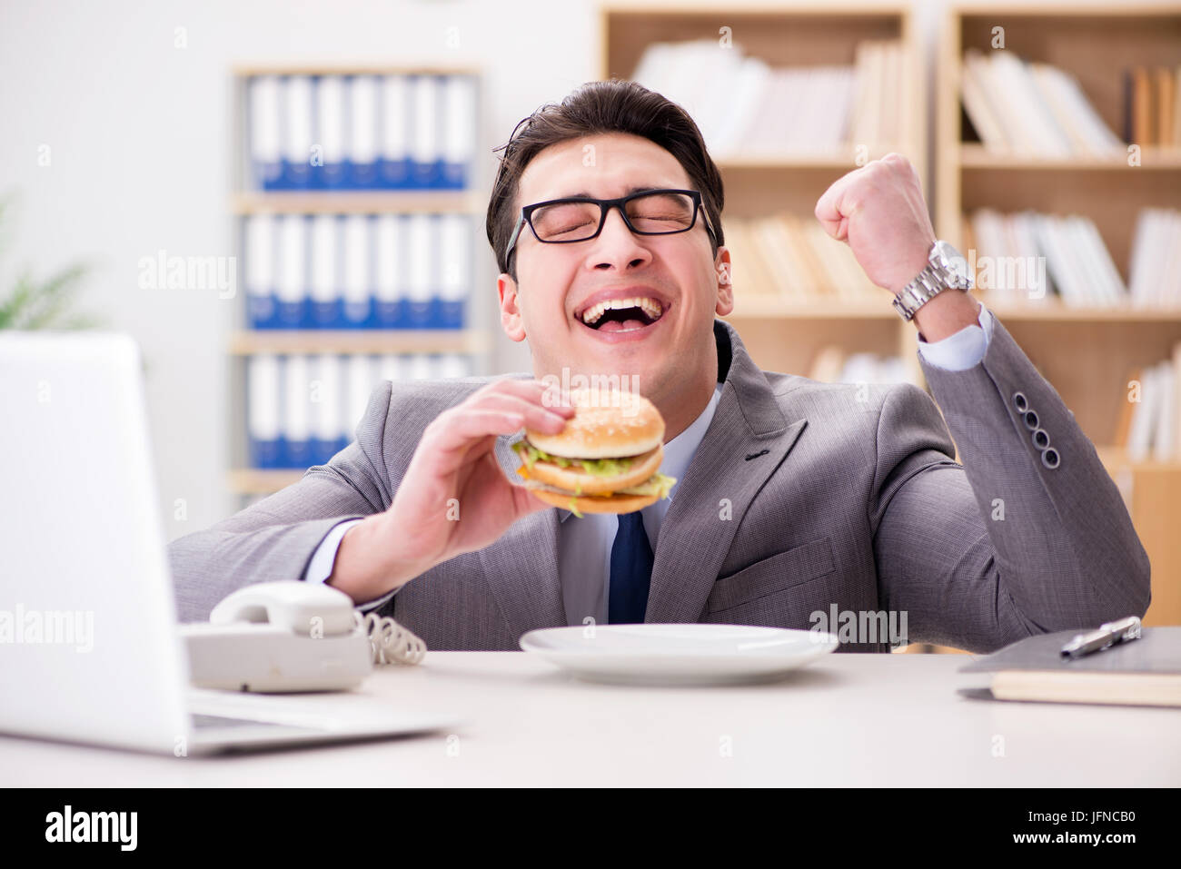 Hungry funny businessman eating junk food sandwich Stock Photo - Alamy
