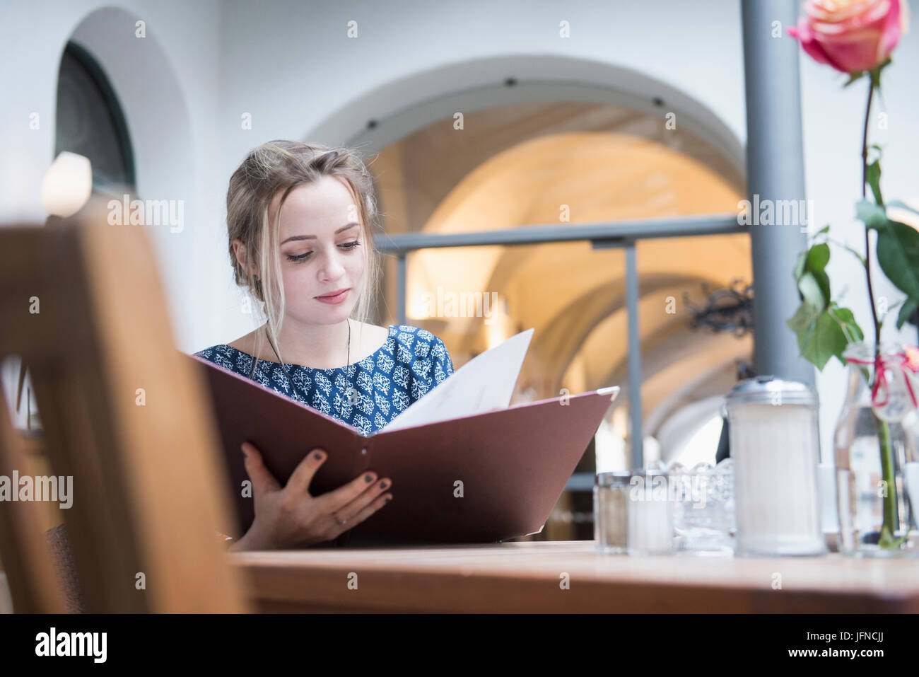 Young woman reading menu at restaurant Stock Photo - Alamy