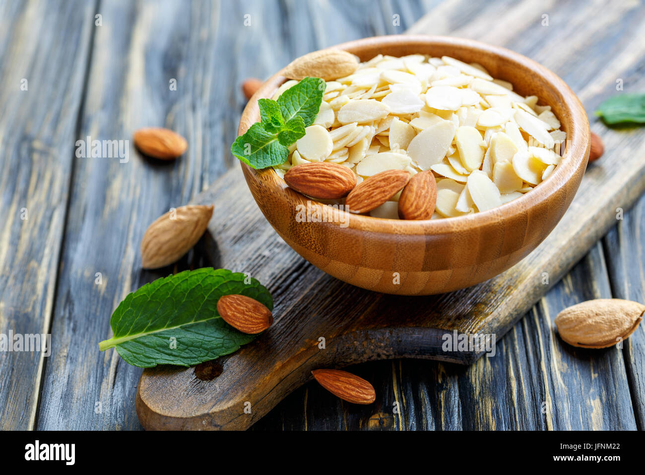 Wooden bowl with almond flakes and whole almonds Stock Photo - Alamy