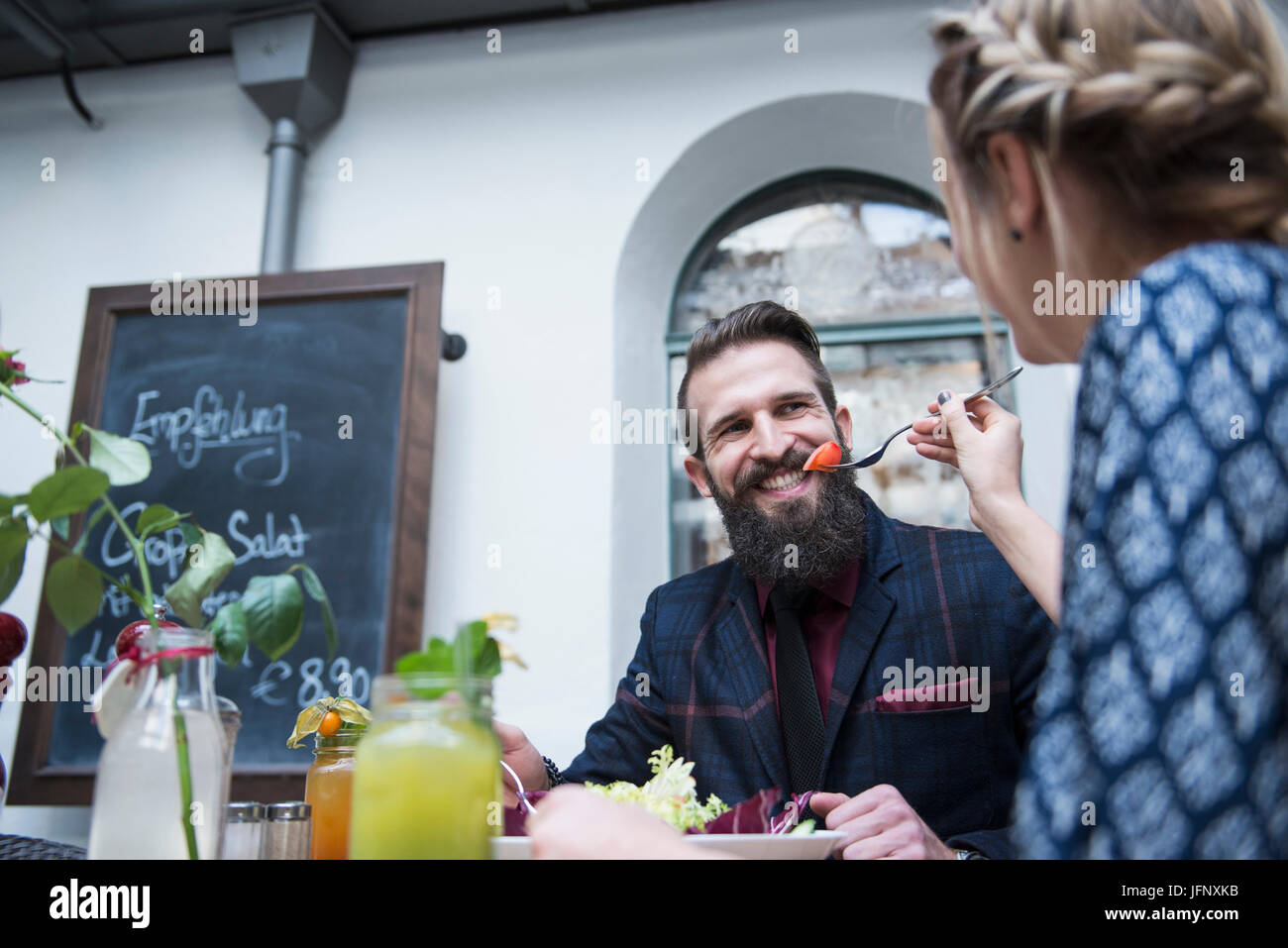 Woman feeding food to man at restaurant Stock Photo - Alamy