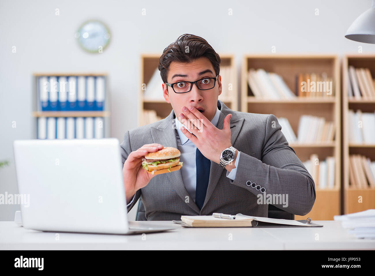Hungry funny businessman eating junk food sandwich Stock Photo - Alamy