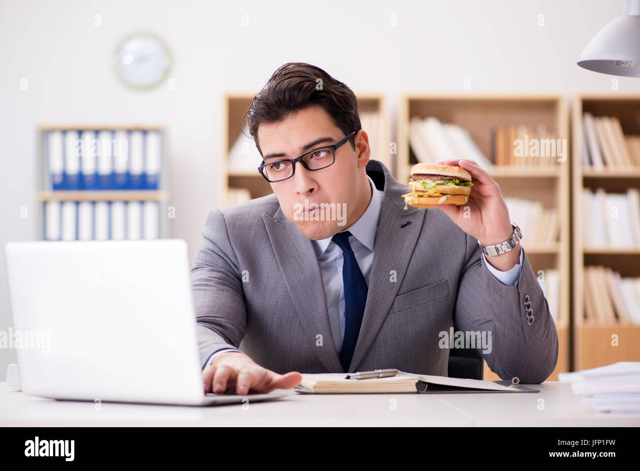 Hungry funny businessman eating junk food sandwich Stock Photo - Alamy