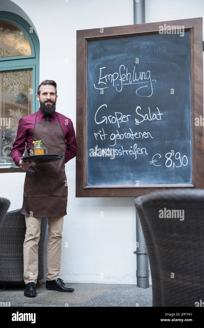 Young waiter standing by chalkboard menu in restaurant Stock Photo - Alamy