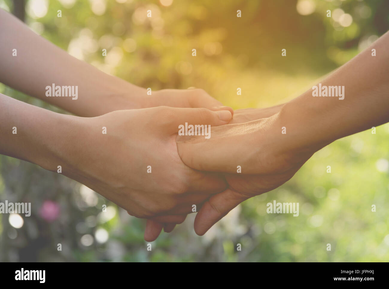 Hand of lady and younger lady holding together on nature background ...