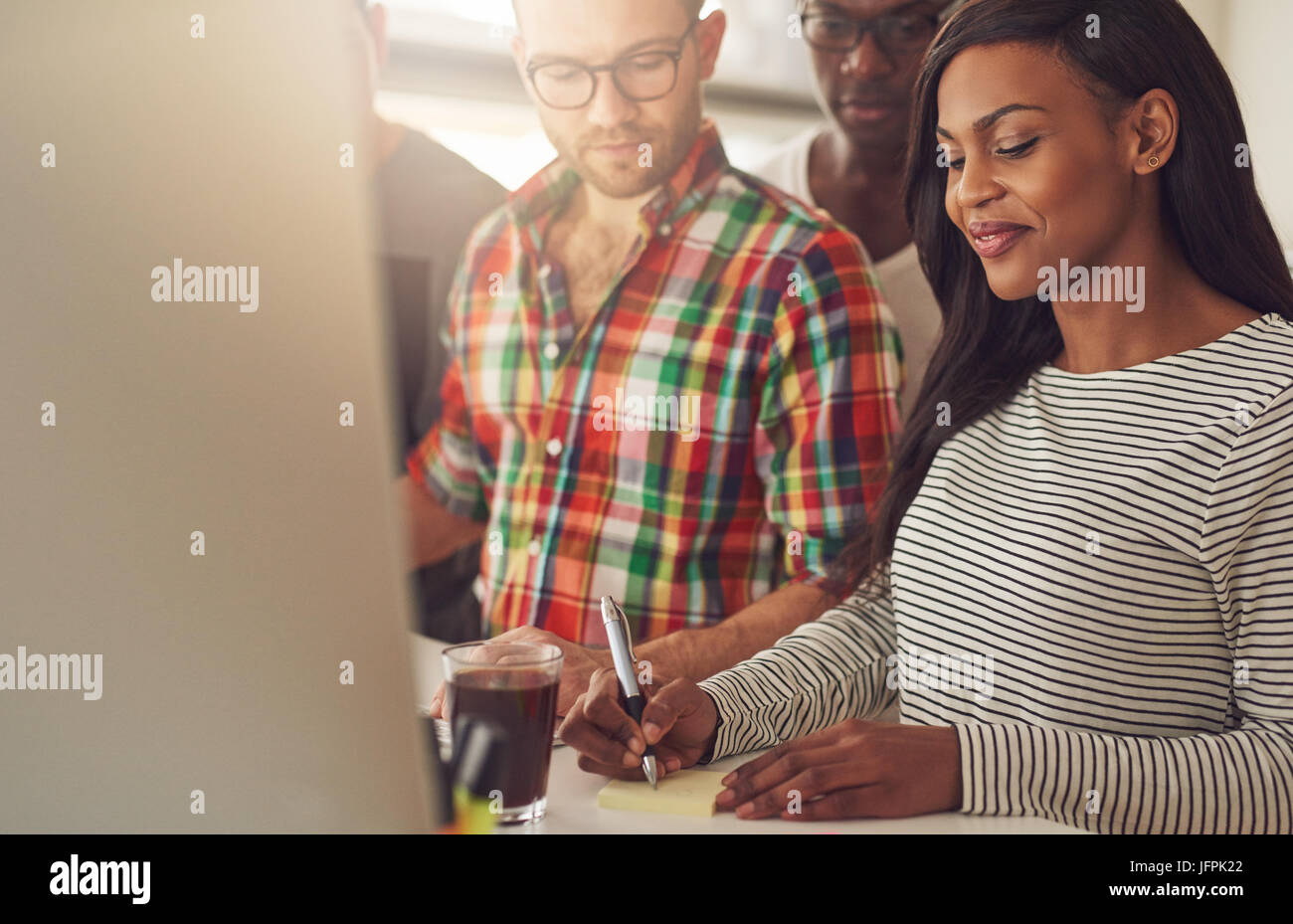 Young woman taking a note while the people looking at her in the office ...
