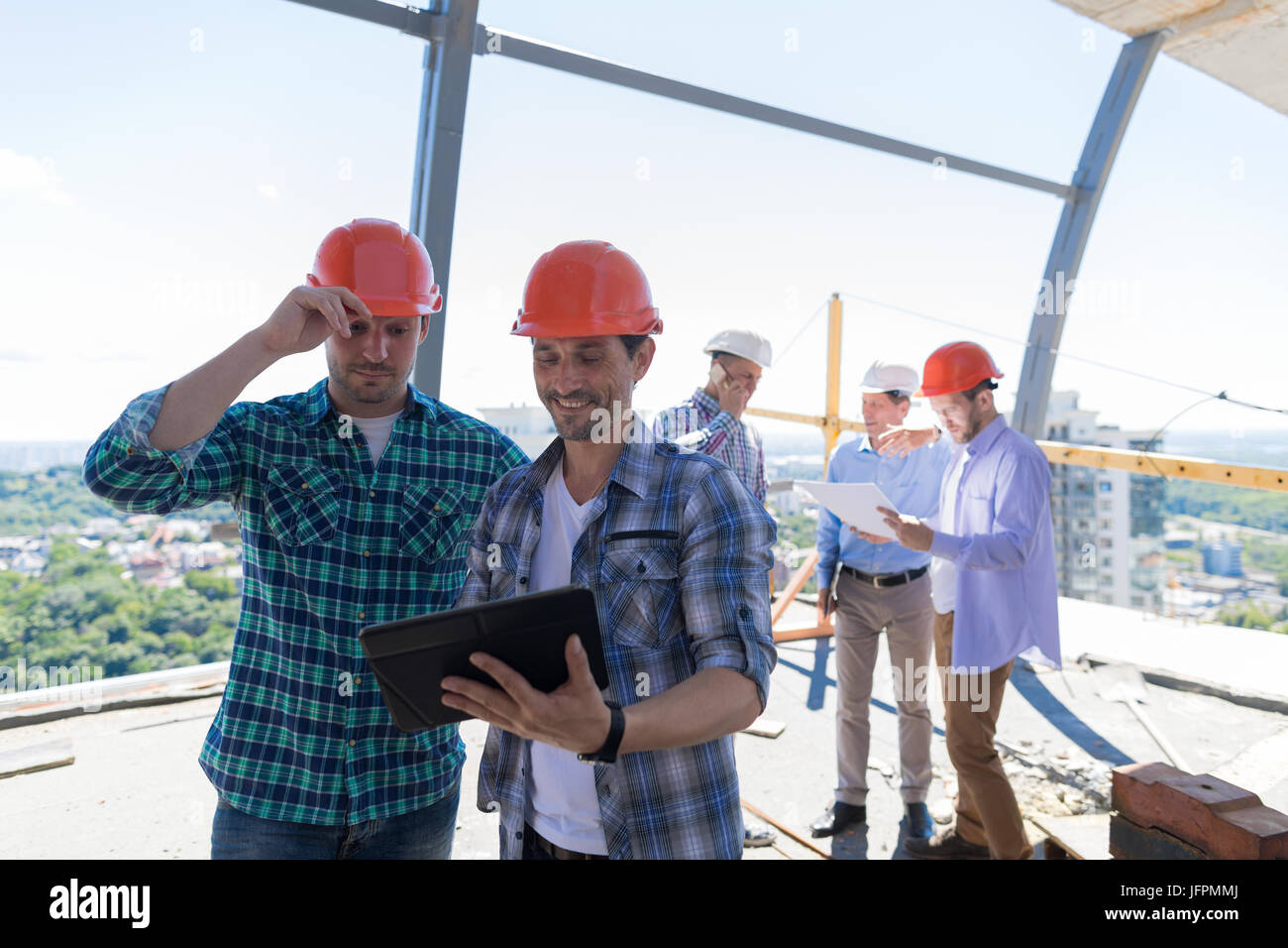 Builders On Site Working With Plan Of Construction Project On Tablet ...