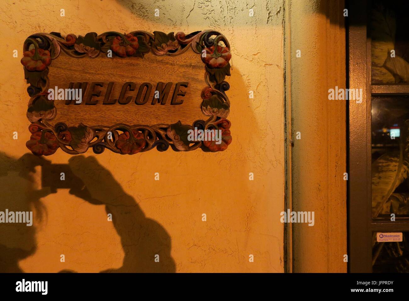 lamp-lit, carved wood "Welcome" sign with photographer's shadow Stock ...