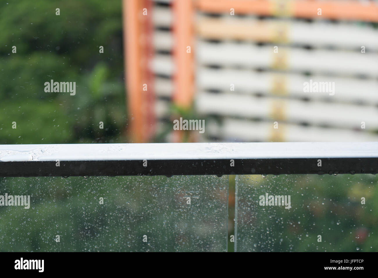 Rain drops on glass balcony, rainy day and apartment in background ...