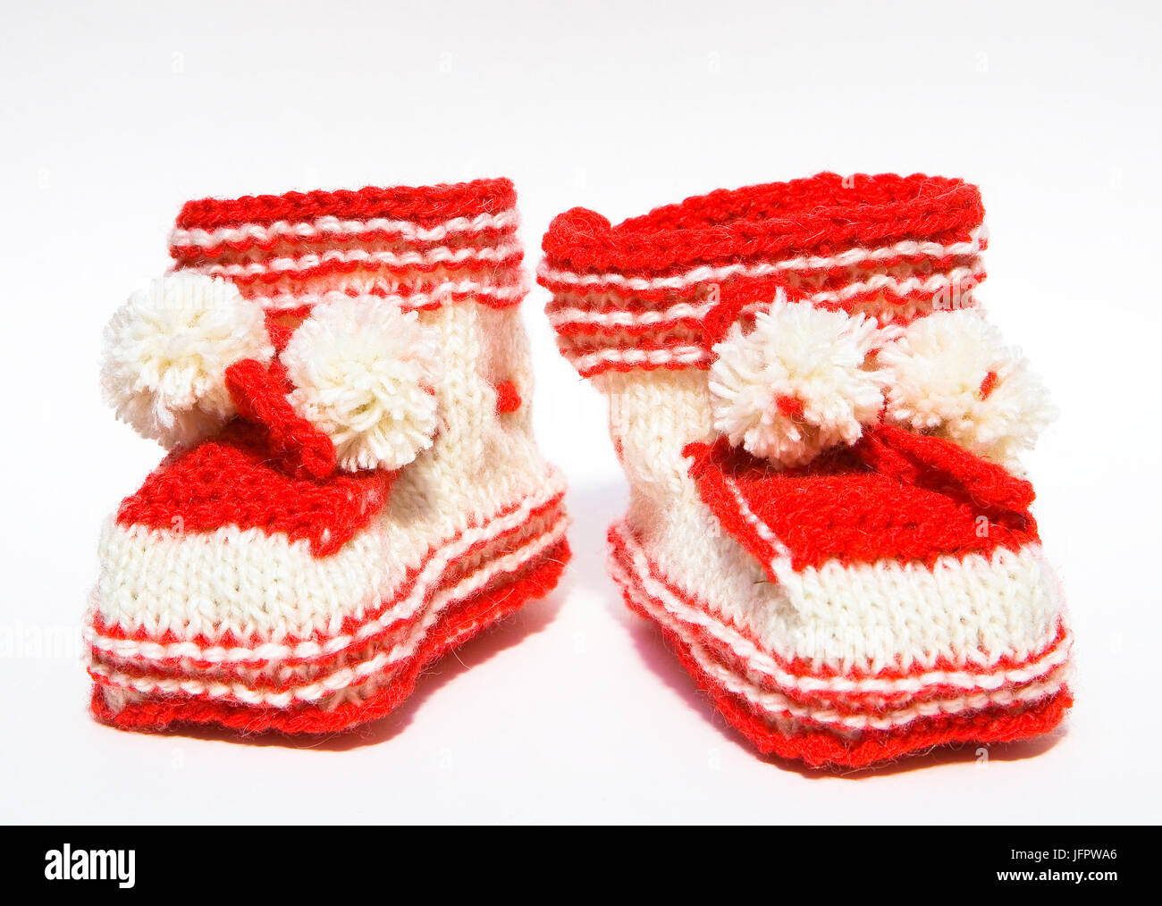 Baby clothes. Red booties with handmade pom-poms Stock Photo - Alamy