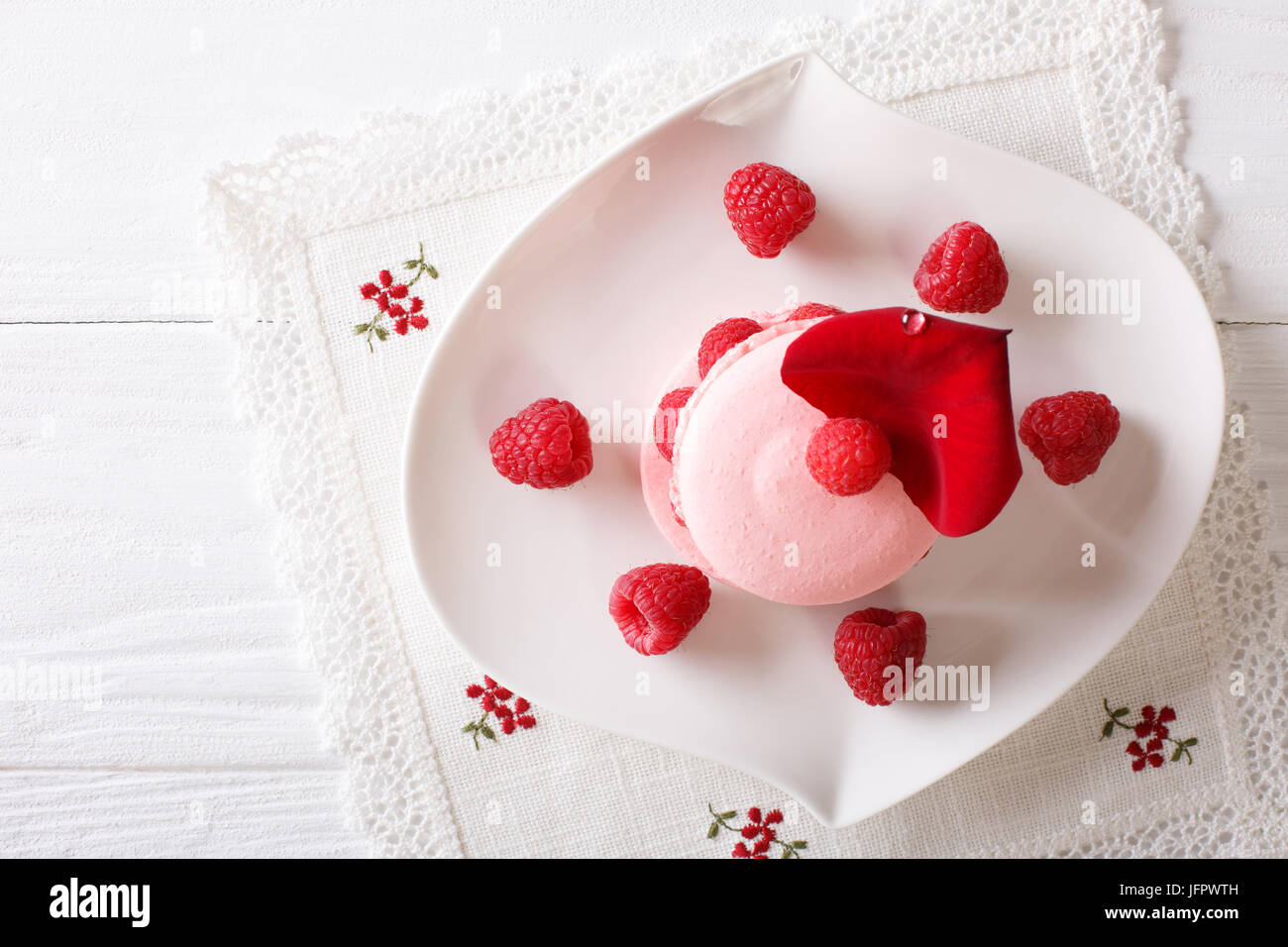 Pink macaroon with raspberry filling close-up on a plate. horizontal ...