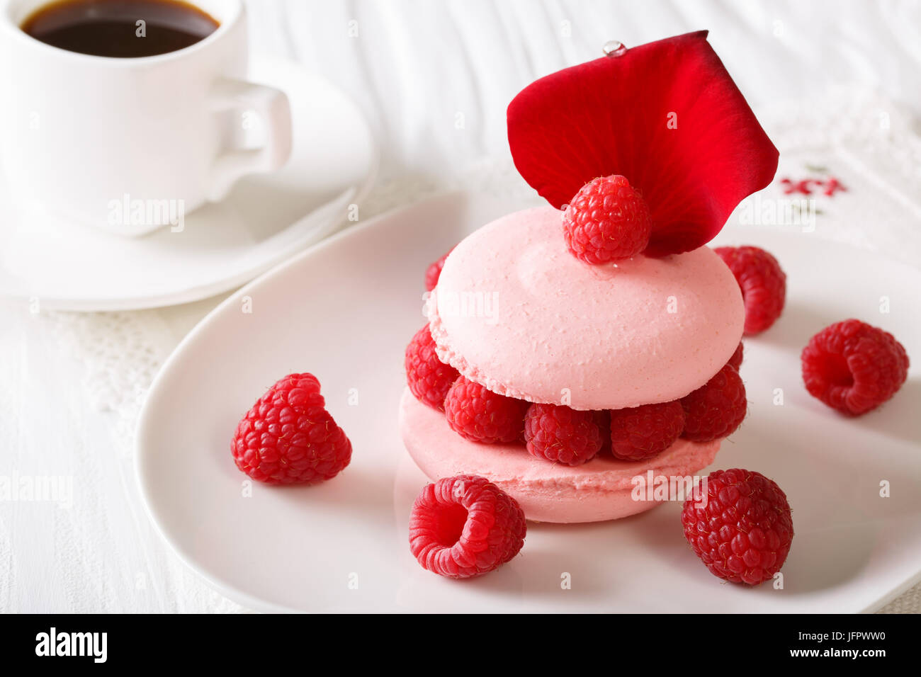 Raspberry macaroon with fresh berries and a cup of black coffee close ...