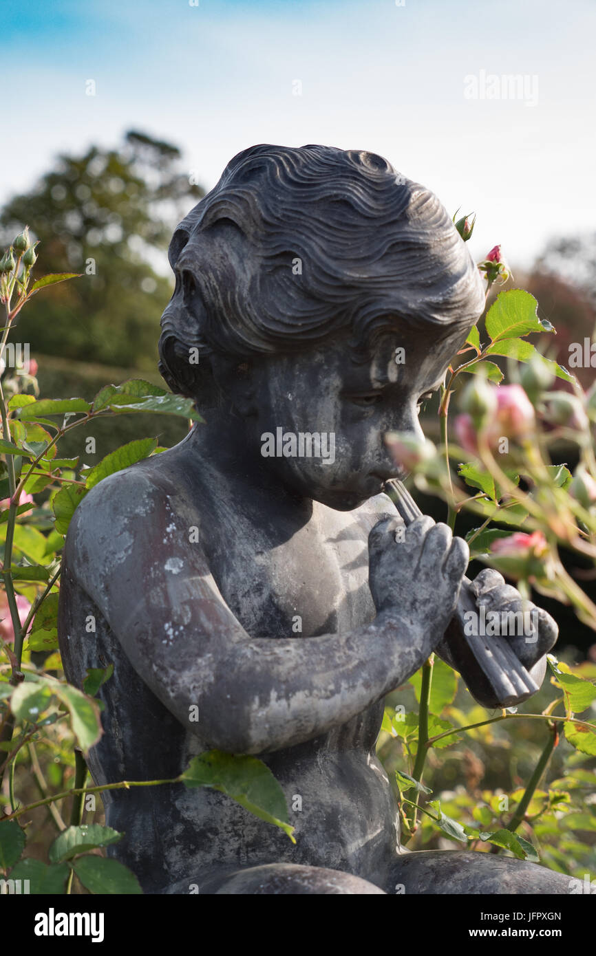Small statue of a cherub playing a flute Stock Photo - Alamy