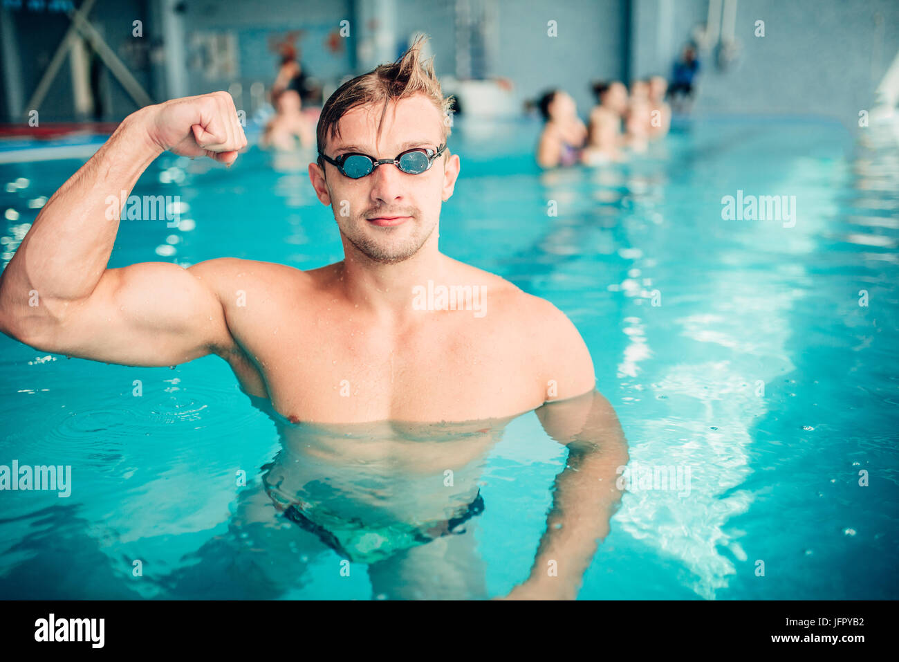 Athletic swimmer shows muscles, indoor swimming pool. Aqua sports ...