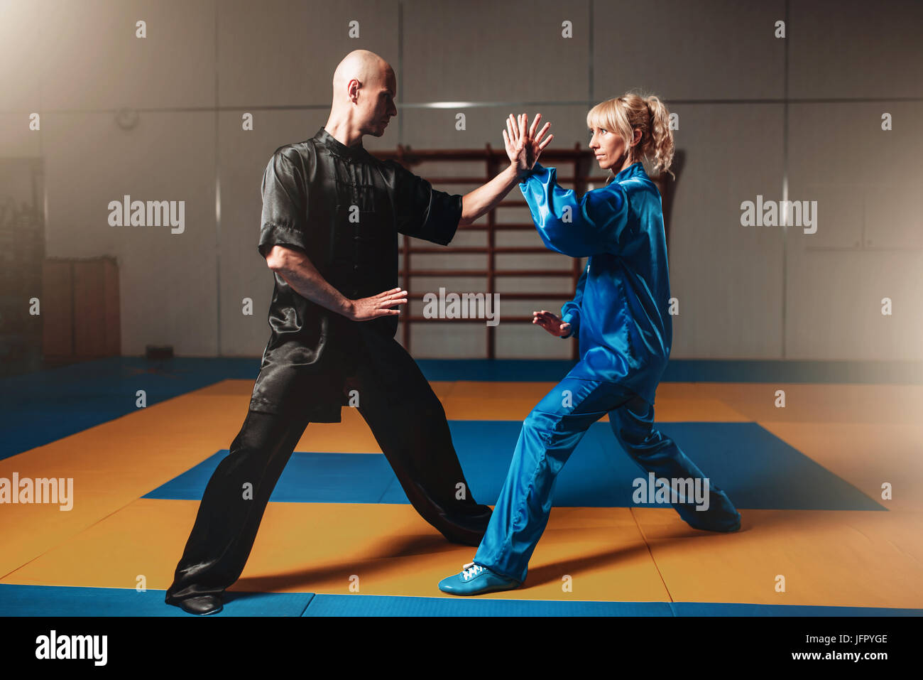 Male and female wushu fighters exercises indoor, martial arts. Sparring ...