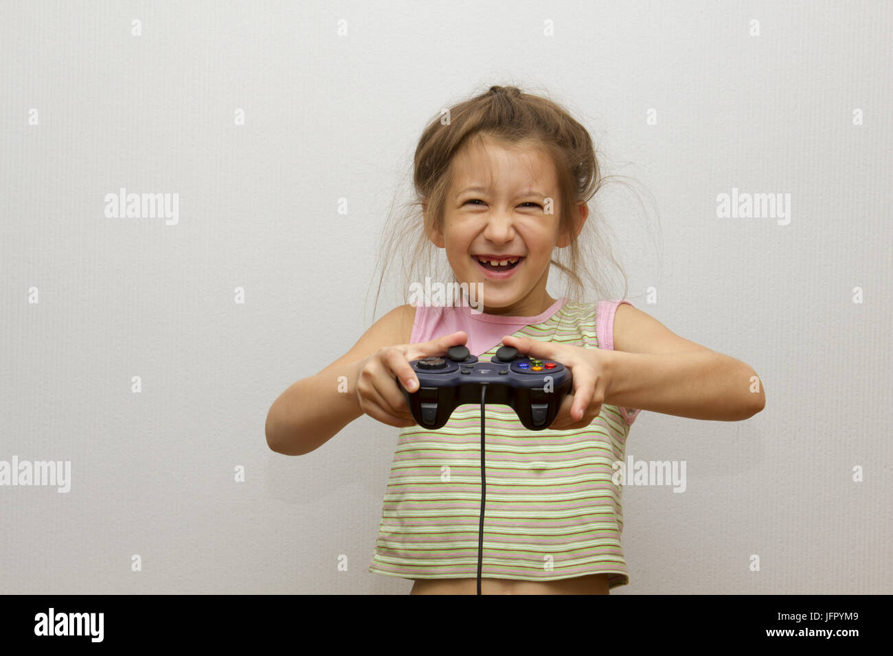 Girl with joystick. Excited little girl playing video game and smiling ...