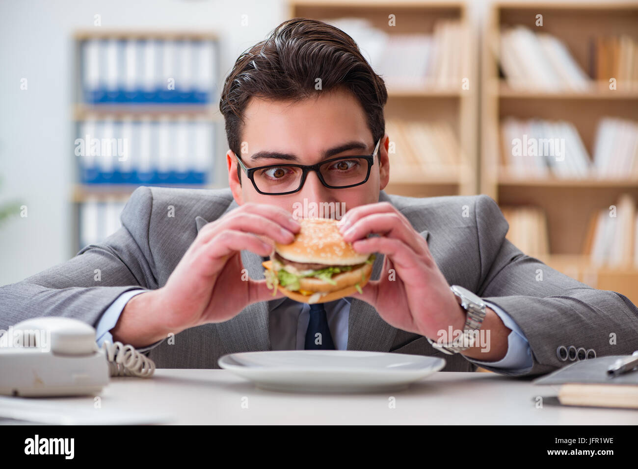 Hungry funny businessman eating junk food sandwich Stock Photo - Alamy