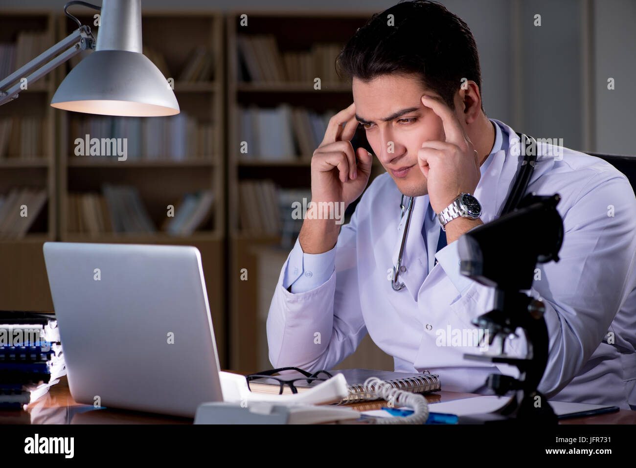 The young doctor working late in the office Stock Photo - Alamy