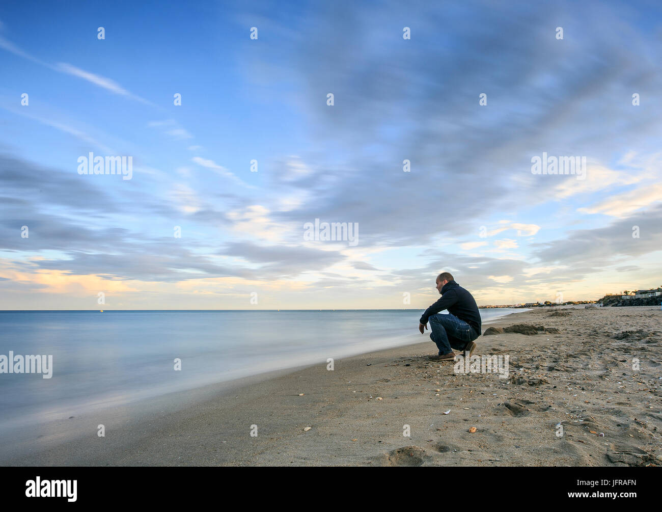 man sitting in a Long exposure photography on the beach Stock Photo - Alamy