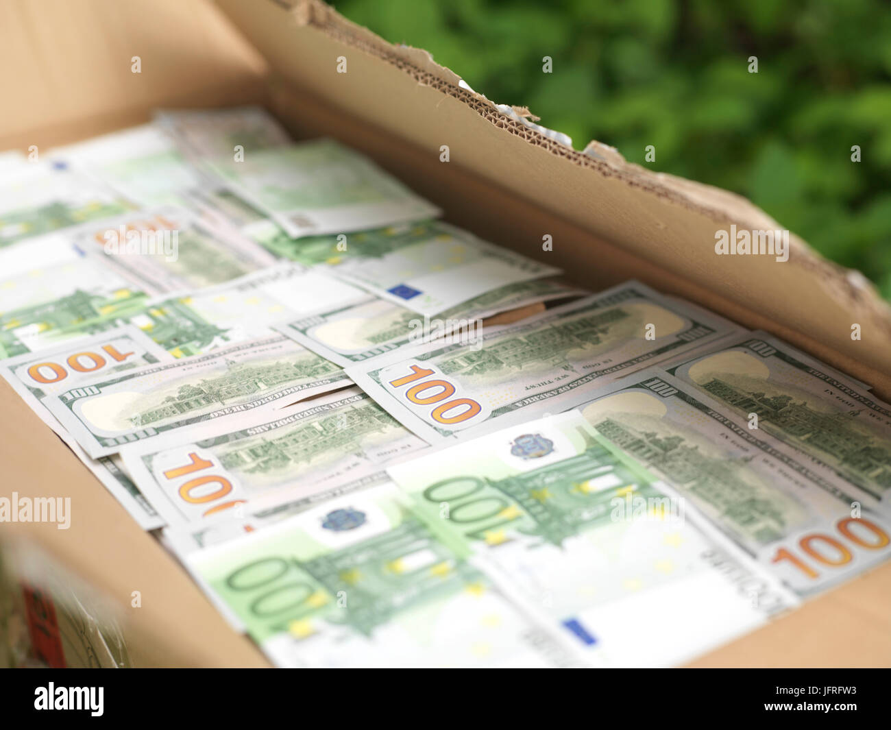 Opened cardboard box full of money, US dollars and Euro. Shallow depth ...