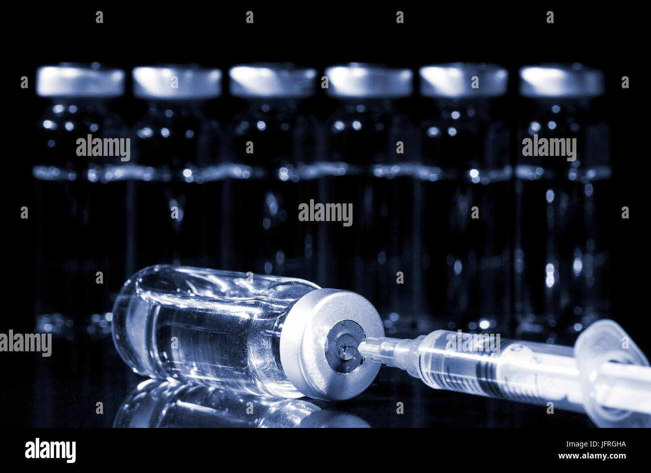 Glass Medicine Vials and Syringe on black background. TInted image ...
