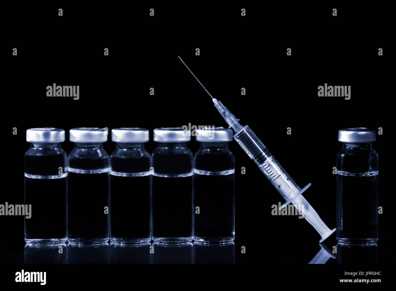 Glass Medicine Vials and Syringe on black background. TInted image ...