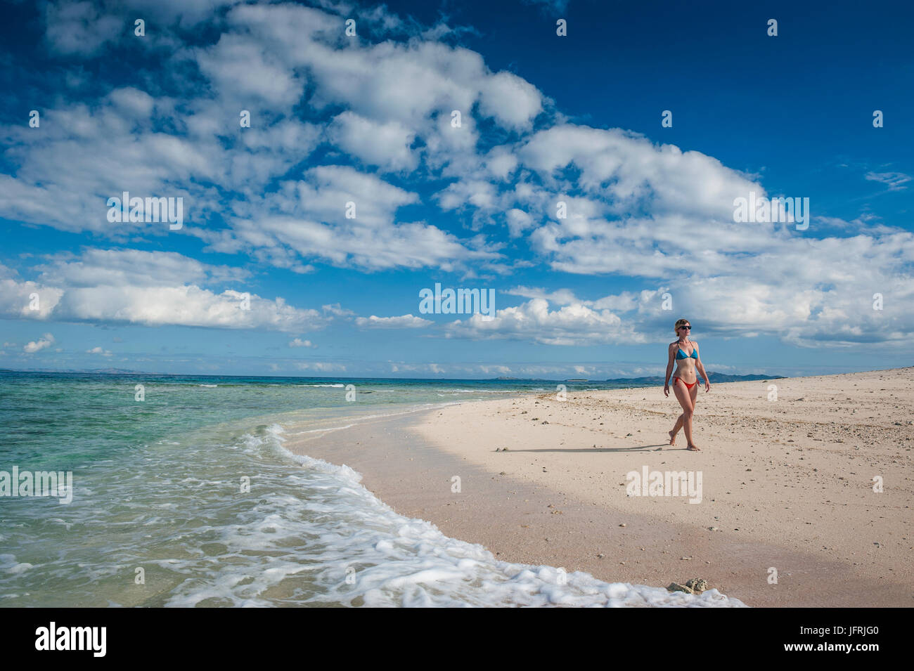 Woman walking along the white sand beach of Beachcomber island ...