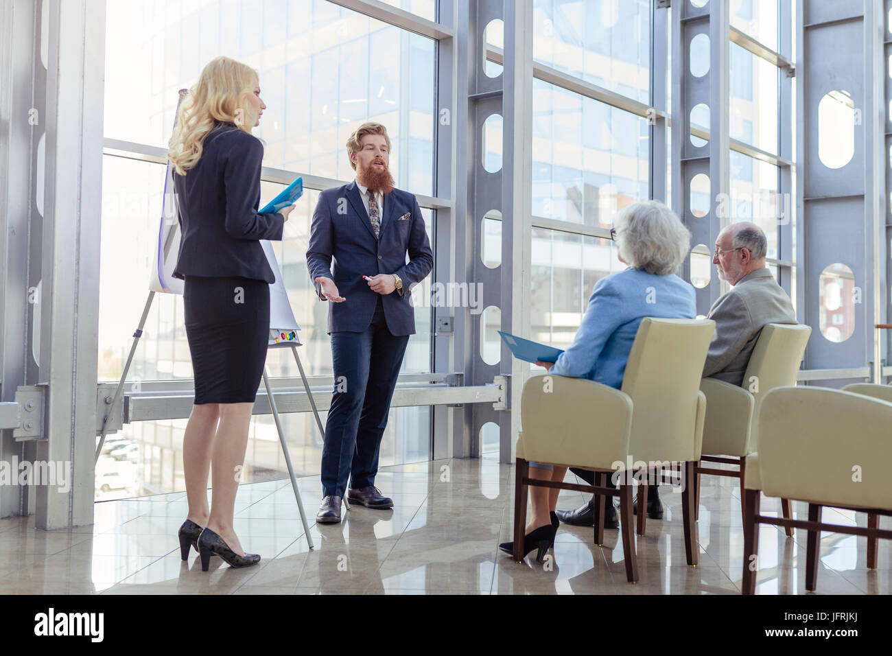 Business people making presentation to senior couple at business center ...
