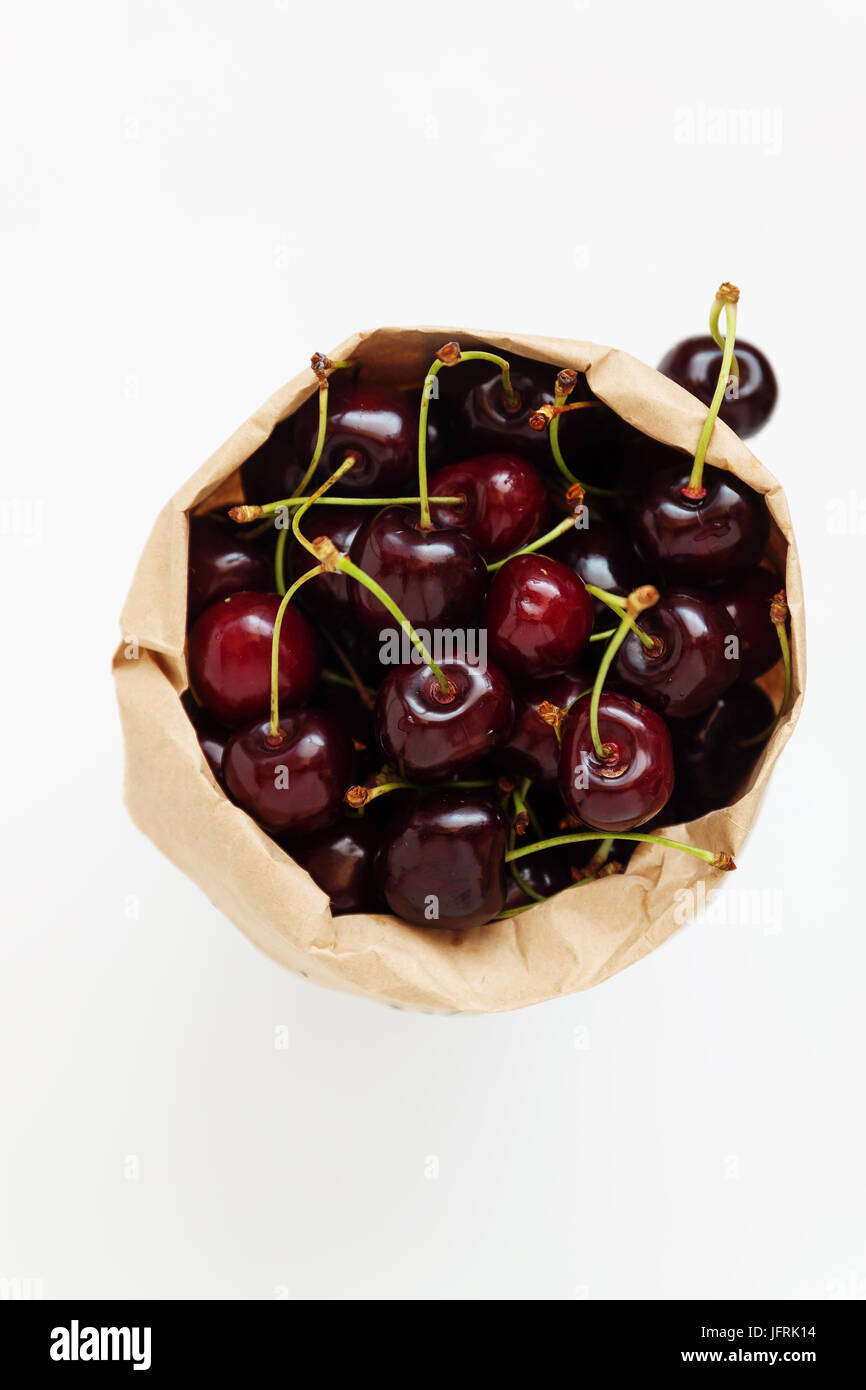 Fresh cherry berries in a paper bag, isolated on a white background ...