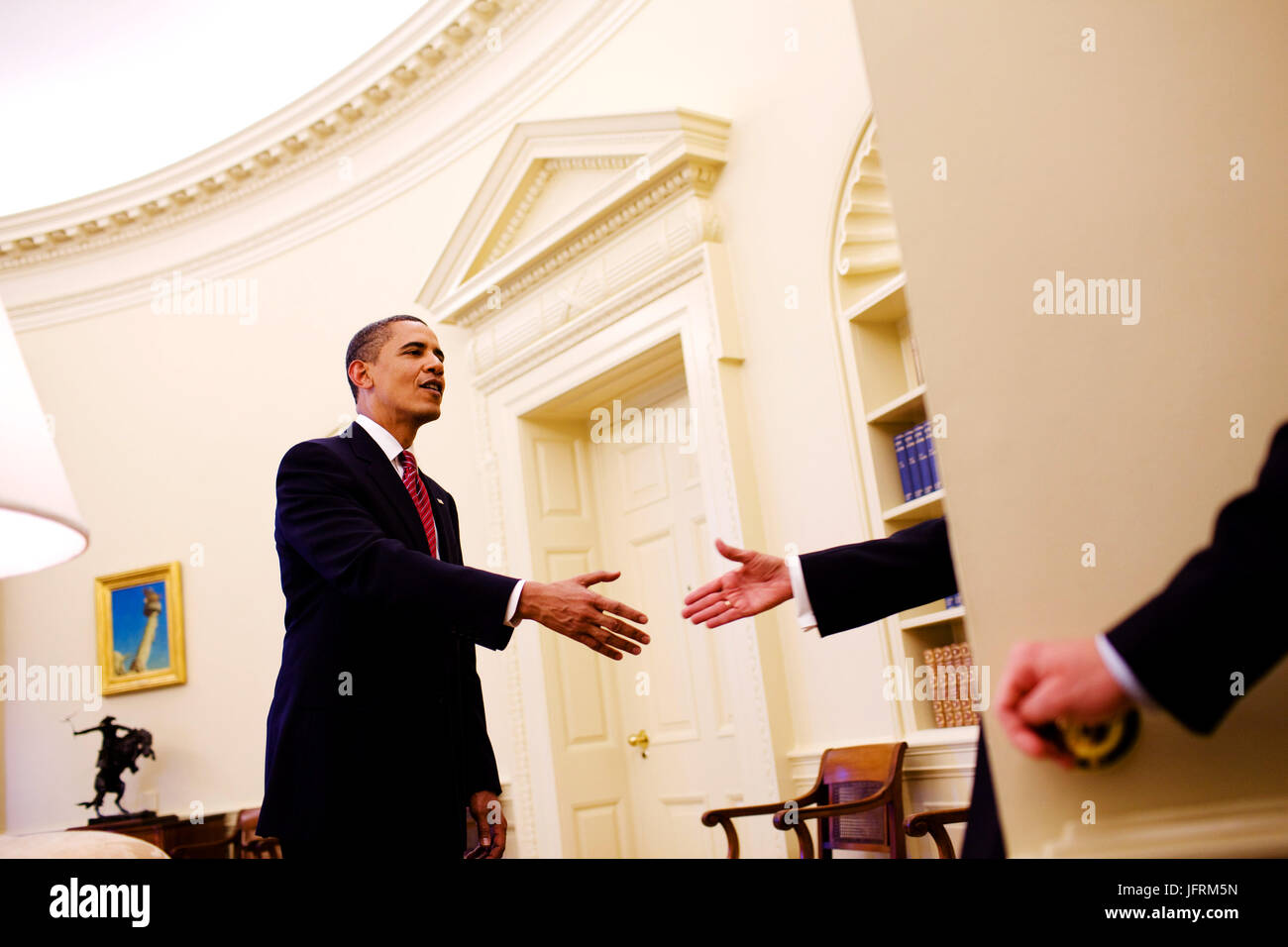 President Barack Obama shakes hands with a guest entering the Oval ...
