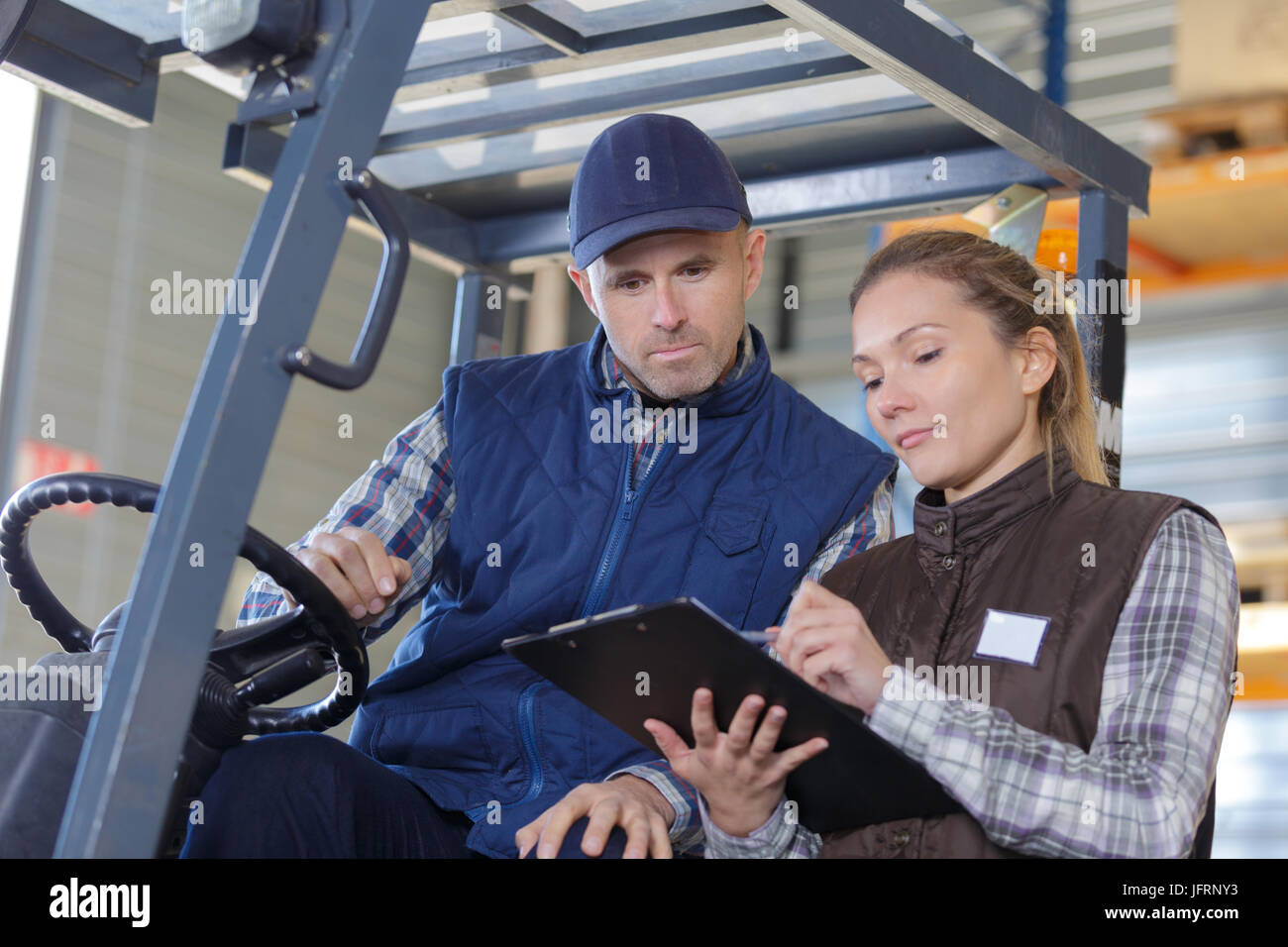 supervisor showing clipboard to forklift driver Stock Photo - Alamy
