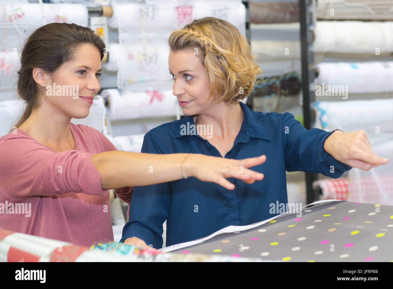 smiling women selecting textiles in fabric store Stock Photo - Alamy