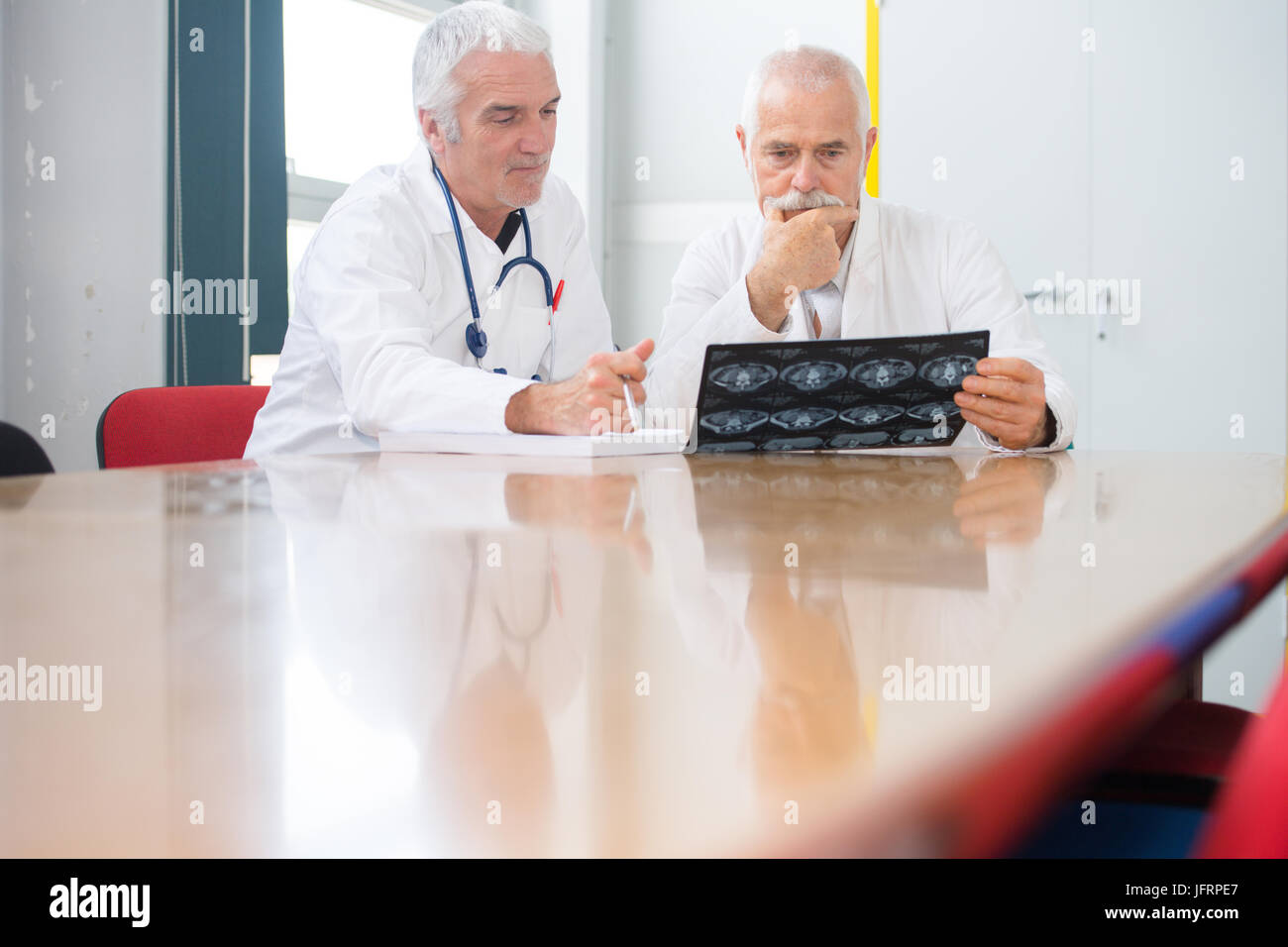 two male doctors discussing x-rays at the table Stock Photo - Alamy