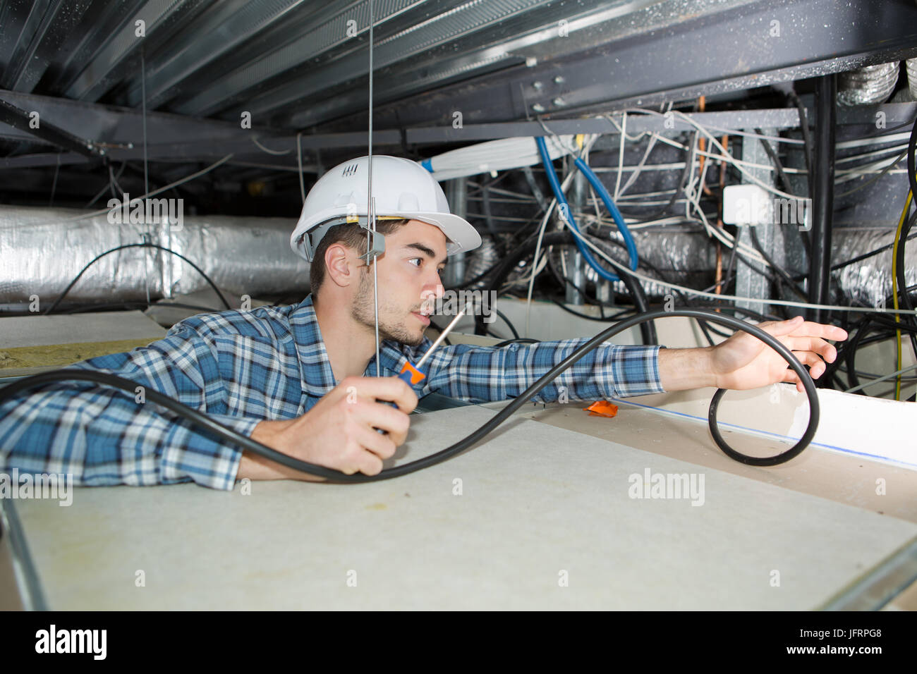 male electrician with screwdriver wiring in building ceiling Stock ...