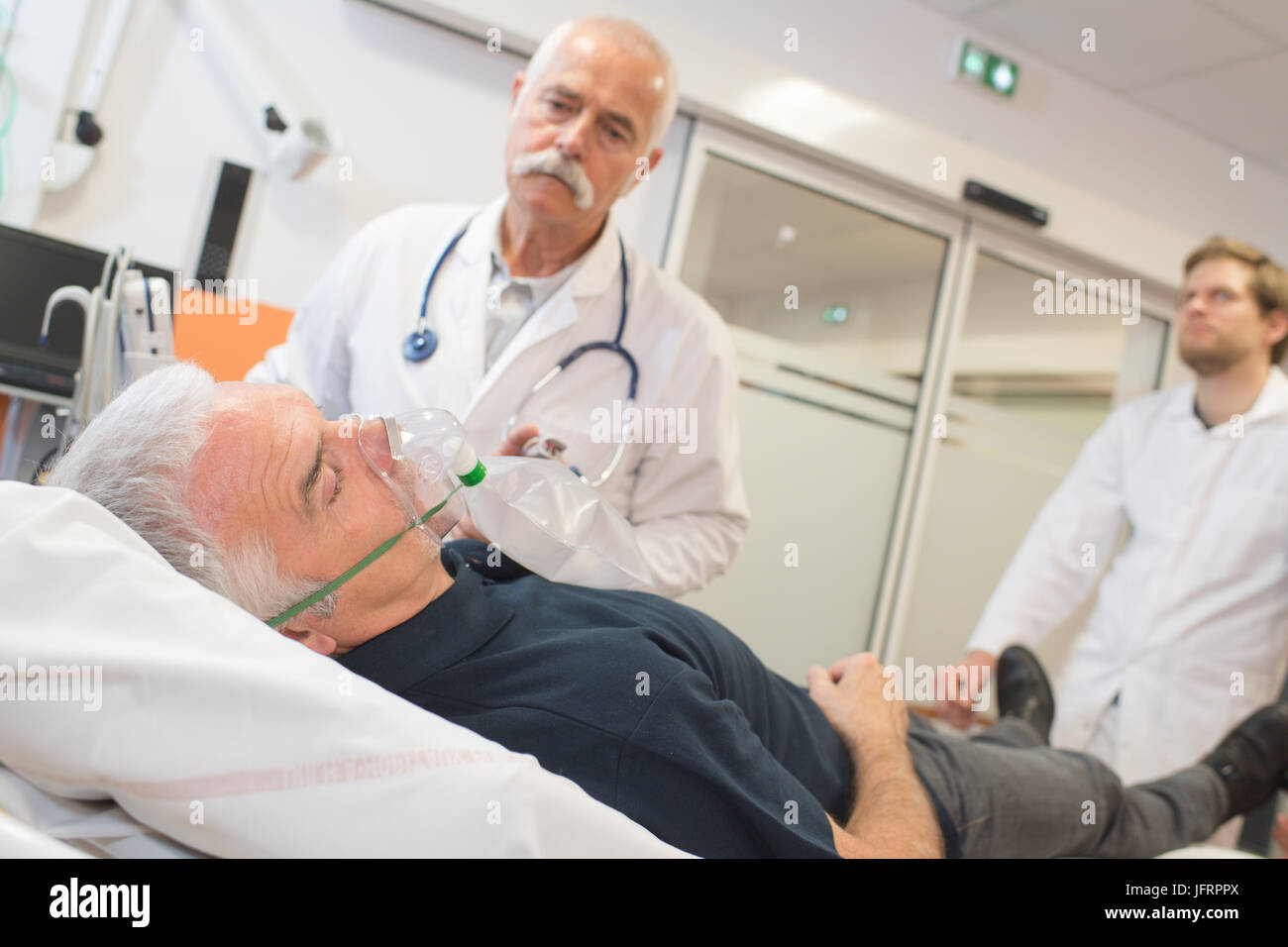 patient wearing oxygen mask in hospital room visited by doctors Stock ...