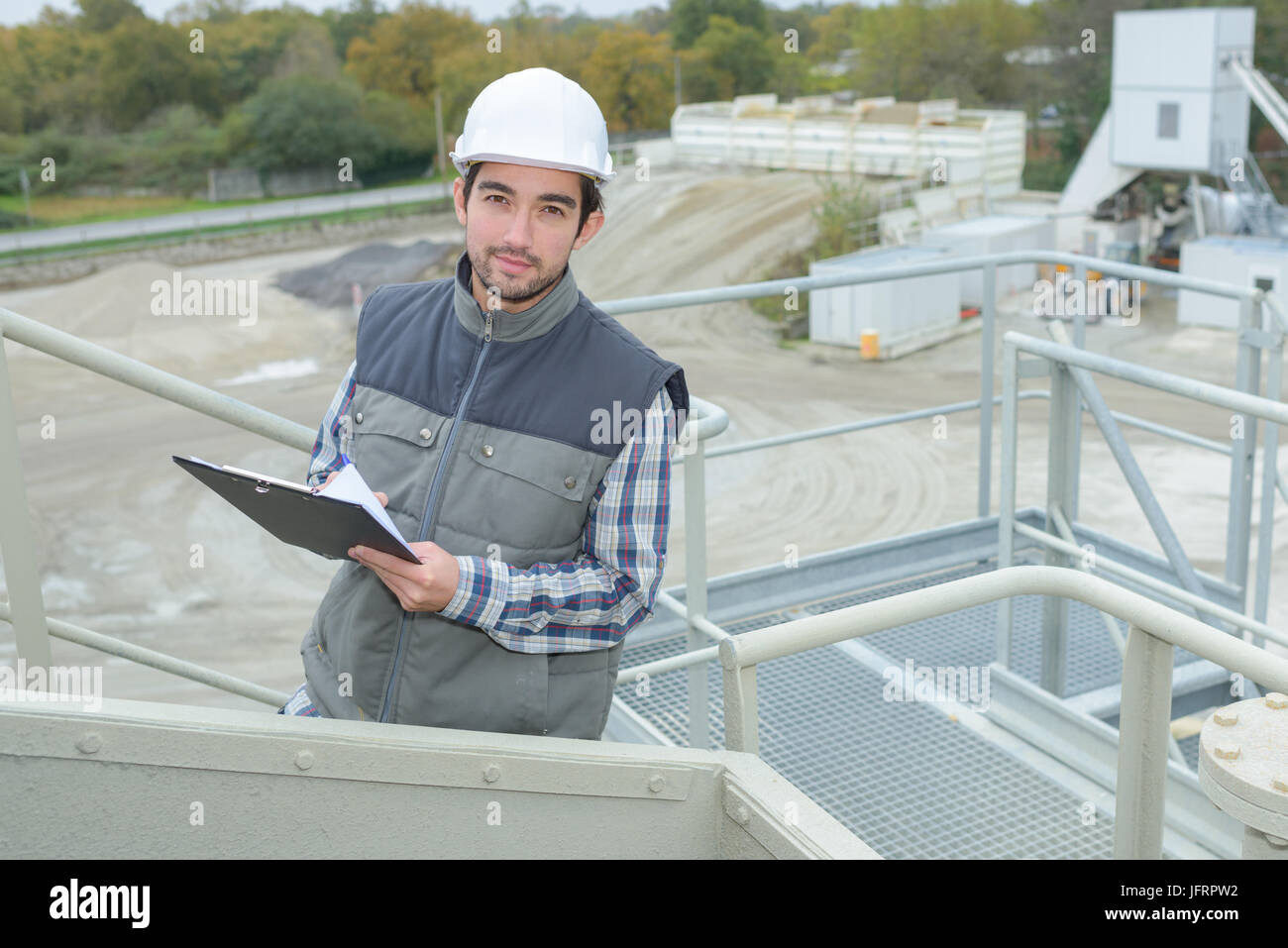 handsome engineer with clipboard near the factory Stock Photo - Alamy