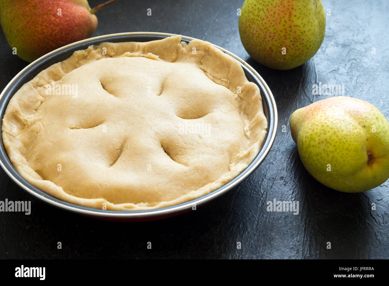 Cooking pear pie. Unbaked shortcrust pie (dough, filling) in baking ...