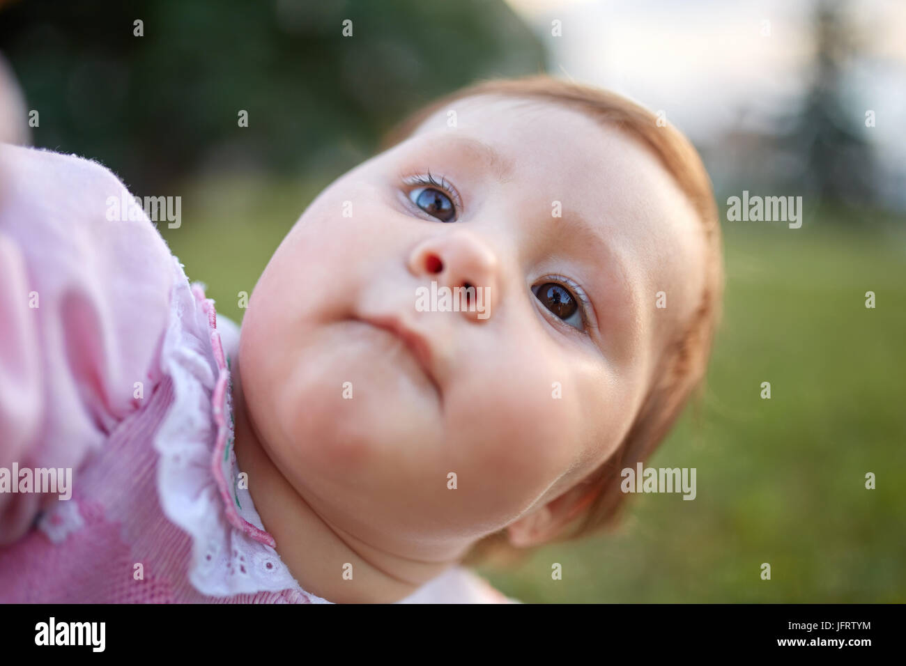 Serious baby thinking on nature green background and looking with ...