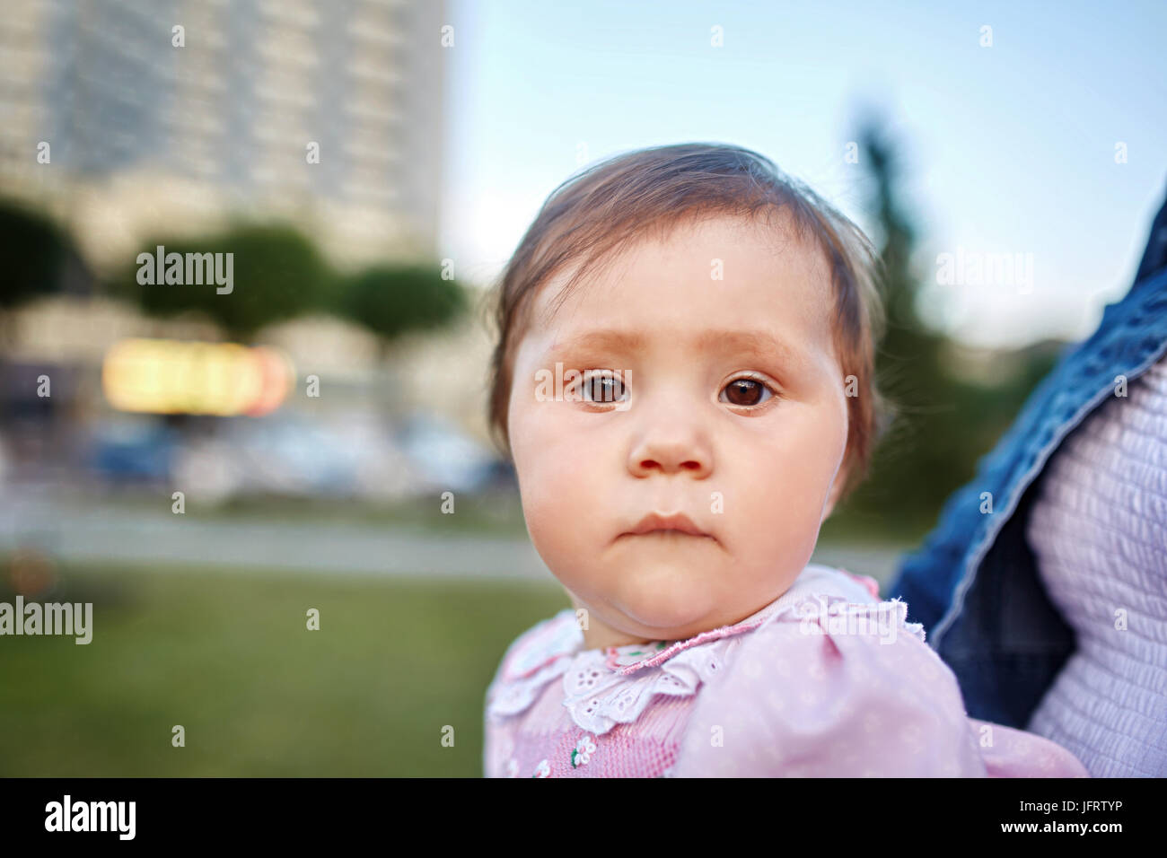 Serious baby thinking on nature green background and looking with ...