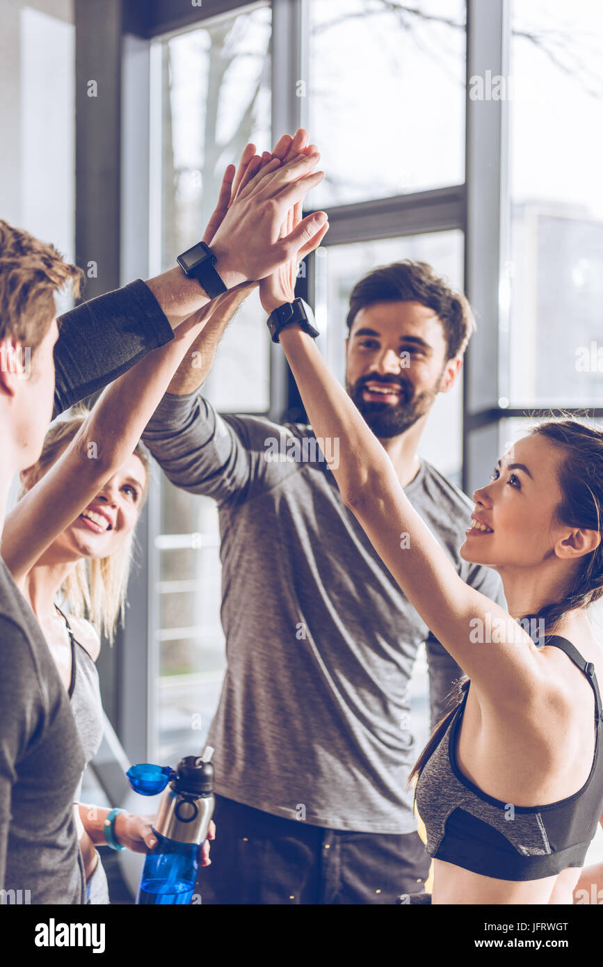 Happy young athletic people in sportswear giving high five in gym Stock ...