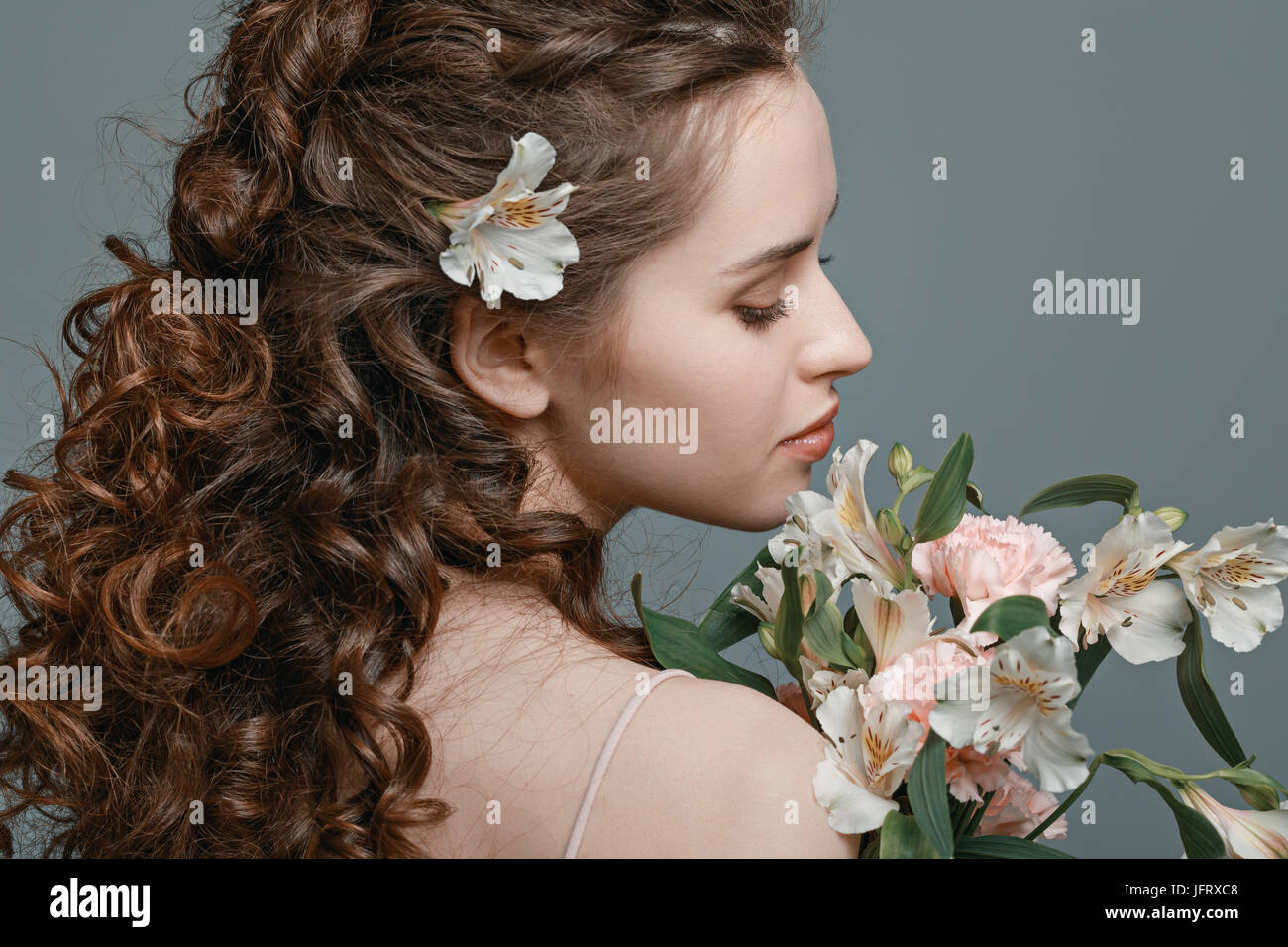 back view of attractive young woman with spring flowers bouquet ...