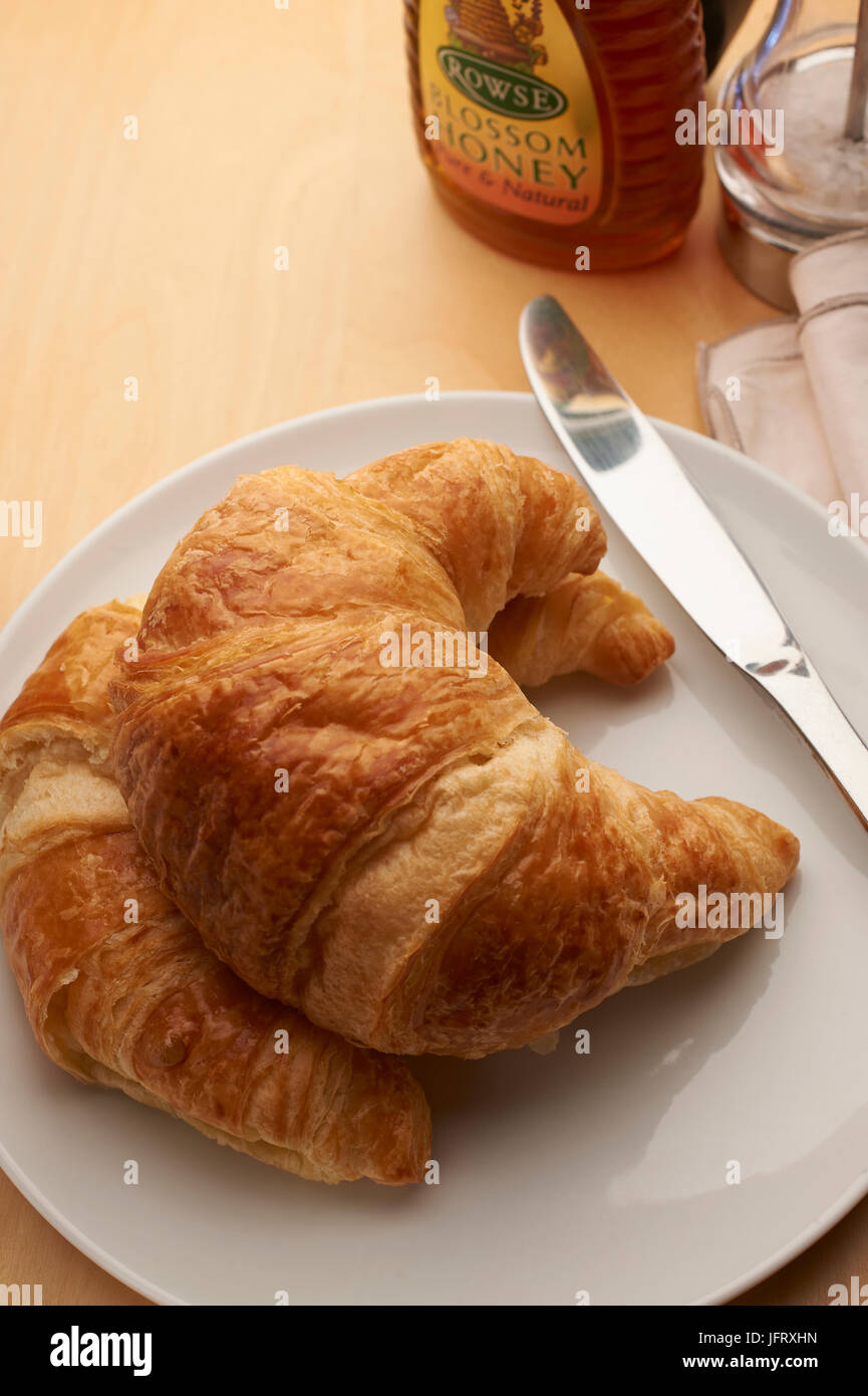A breakfast table with croissant and honey Stock Photo - Alamy