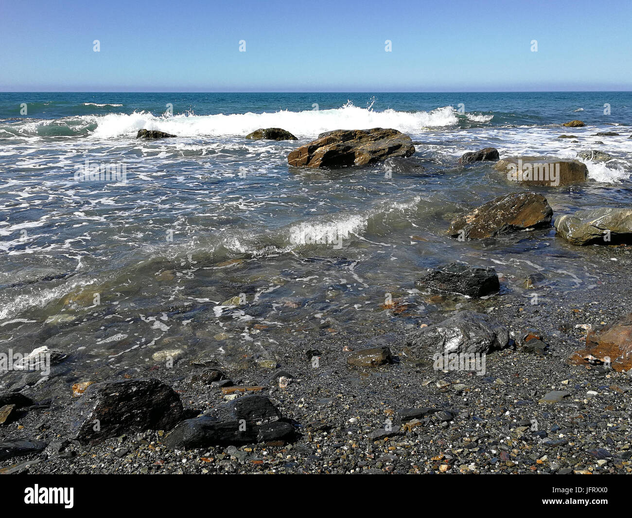 Beach with rocks and soft waves Stock Photo - Alamy