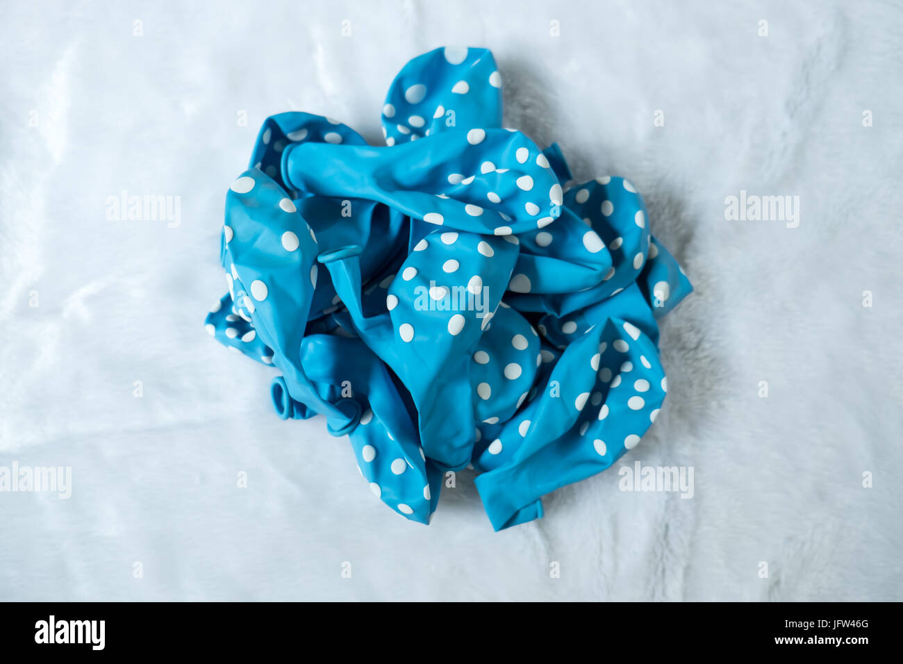 Deflated blue pastel with white dots rubber air balloon isolated over ...