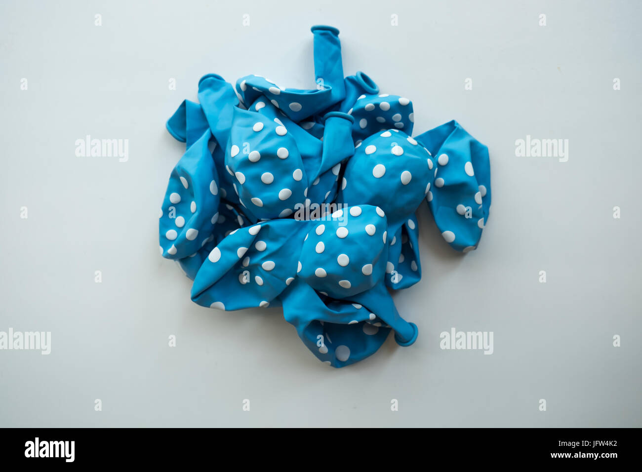 Deflated blue pastel with white dots rubber air balloon isolated over ...